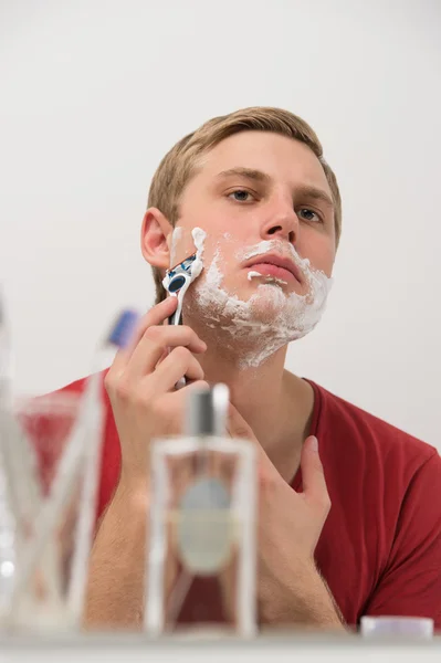 Young man shaving in the bath. - Stock Image - Everypixel