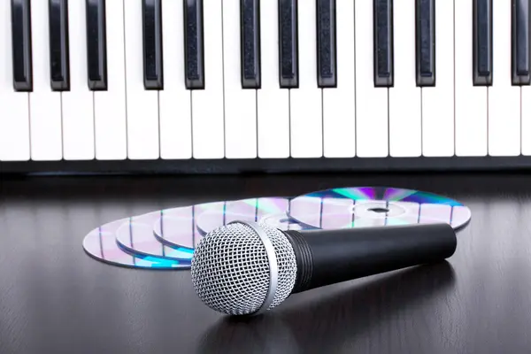 Microphone, cd and piano keyboard on black table - Stock Image - Everypixel