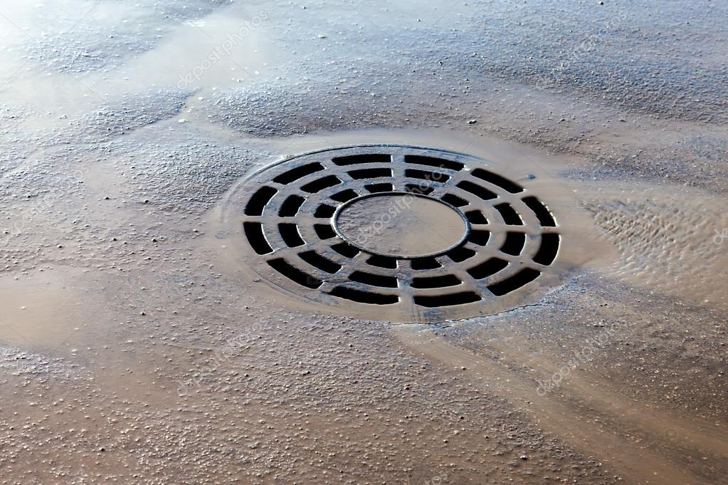 Melted water flows down through the manhole cover on spring day — Stock ...