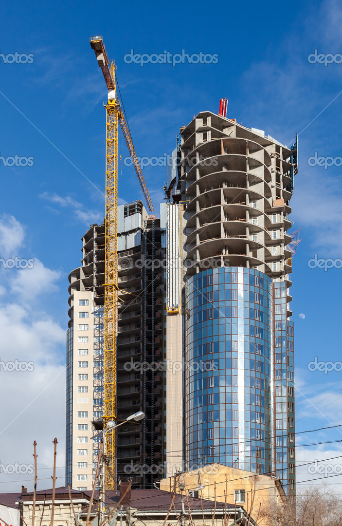 Tall buildings under construction with cranes against a blue sky ...