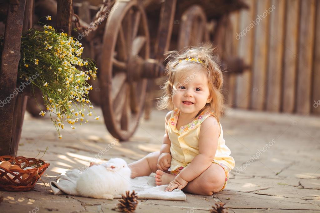 Little girl playing with rabbit in the village. Outdoor. Summer ...