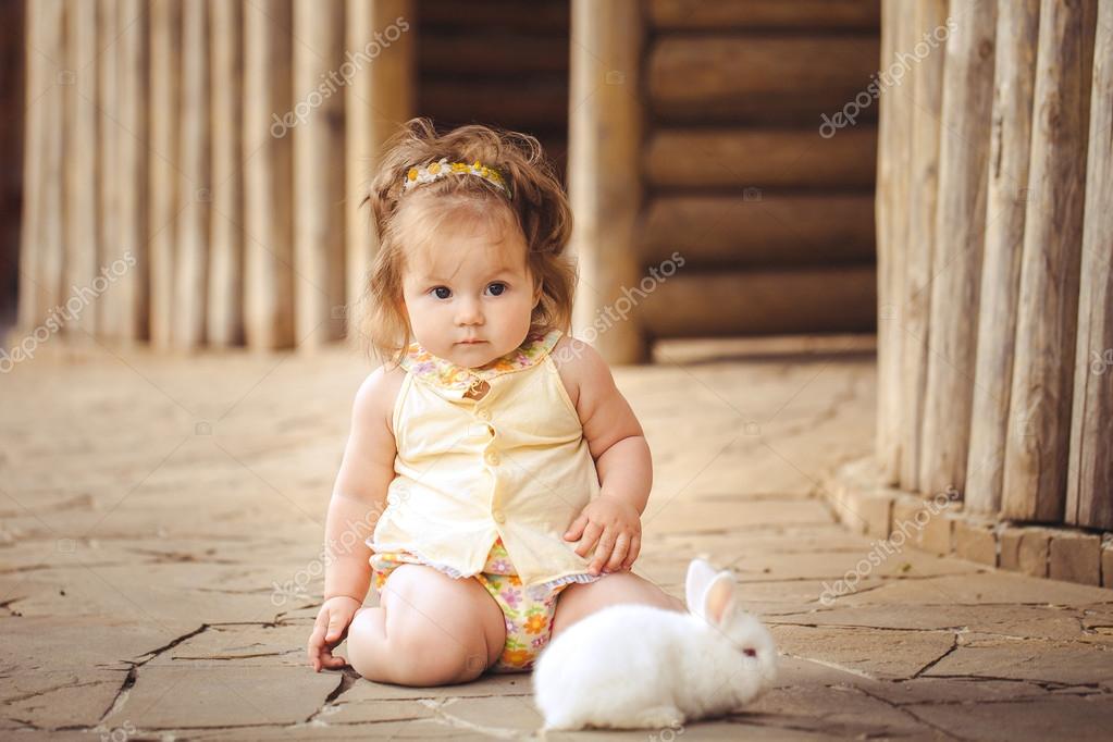 Little girl playing with rabbit in the village. Outdoor. Summer ...