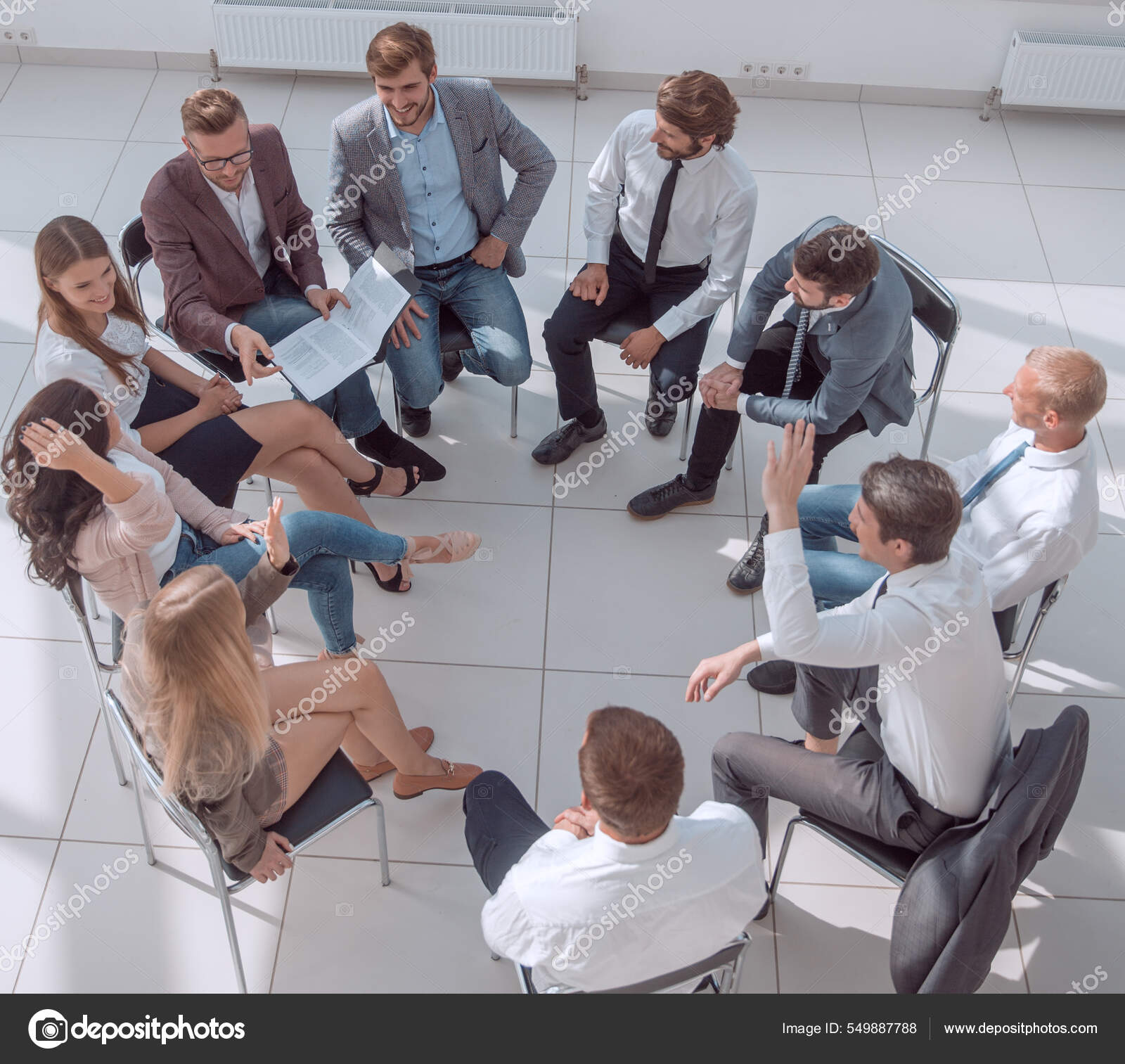 Team of young employees sitting in a circle in the conference room ...
