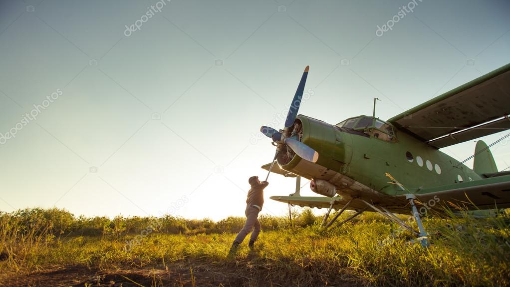 Pilot is starting engine of vintage plane Stock Photo by ©bigdan 31324561