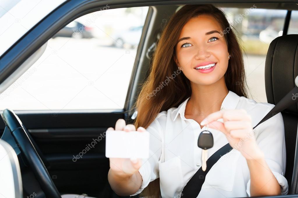 Girl in a car showing a key and an empty white card Stock Photo by ...
