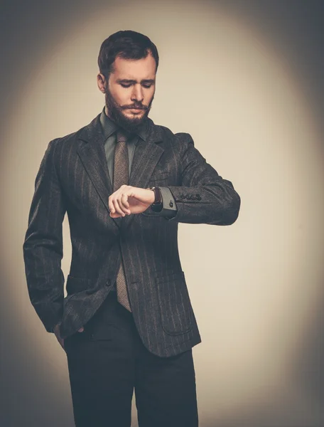 Handsome well-dressed man with beard looking at his wrist watch - Stock ...