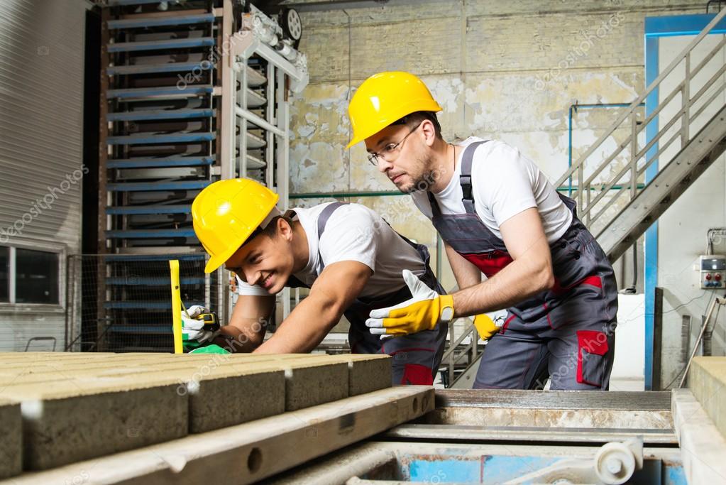 Worker and foreman in a safety hats performing quality check on a ...