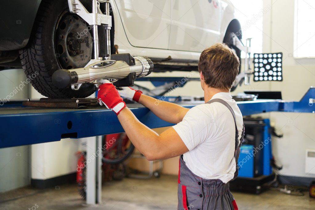 Young serviceman checking wheel alignment in a car workshop — Stock ...