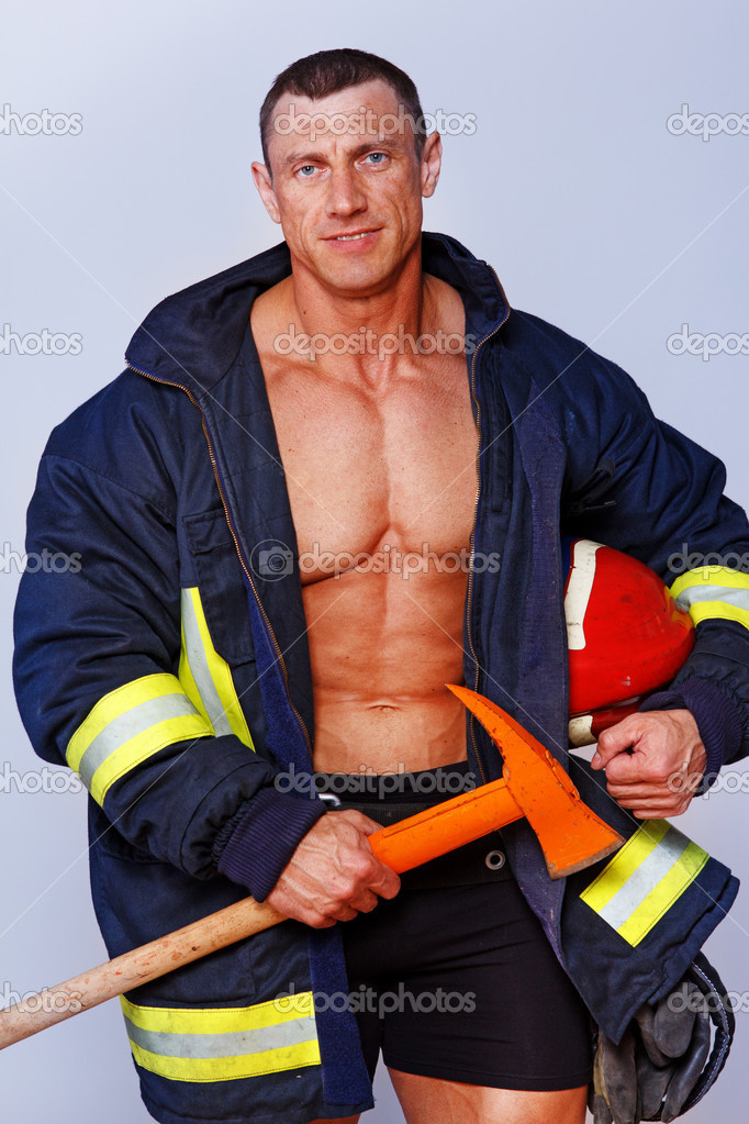 Portrait of handsome man posing on black background in fireman c ...