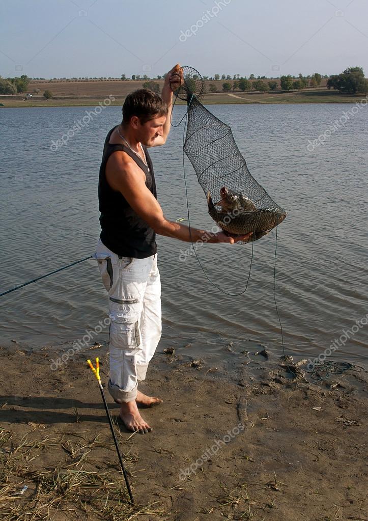 Las manos de los pescadores levantan una red con peces 2024
