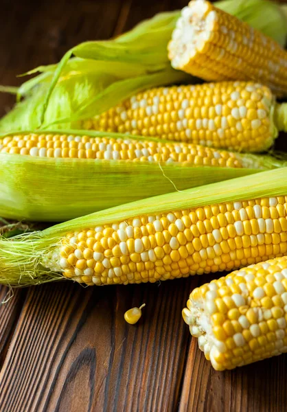 Fresh sweet corn with leaves on cobs on wooden table, closeup, top view ...