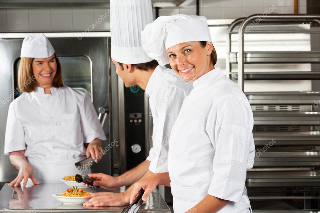 Female Chef With Colleagues In Commercial Kitchen Stock Photo by ...