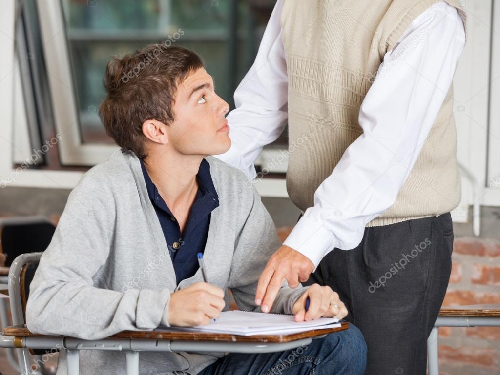 Profesor Explicando El Examen A Estudiante En El Aula: Fotografía De AB