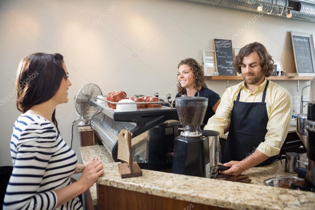 Cliente mirando a los baristas haciendo café en la cafetería 2023