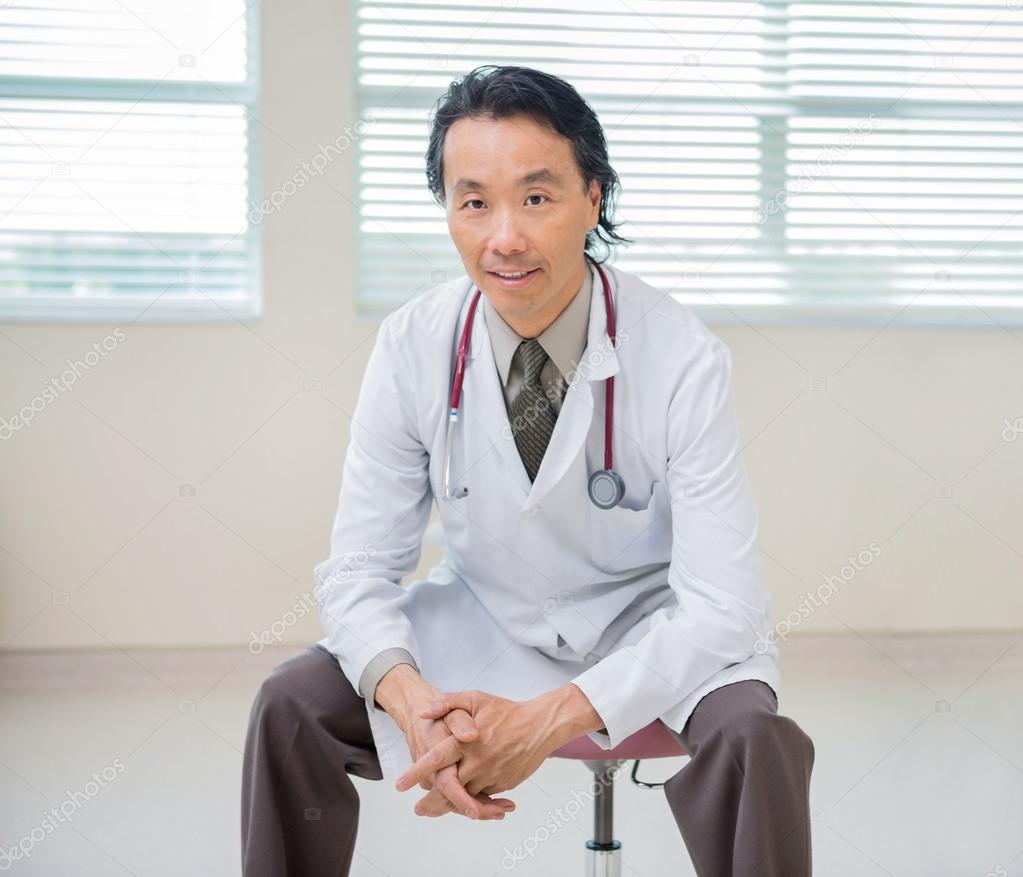 Doctor Sitting At Hospital Room With Patient In Background Stock Photo ...