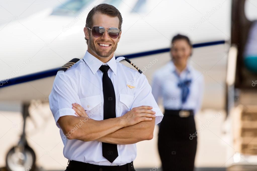 Confident Pilot Against Stewardess And Private Jet Stock Photo by ...
