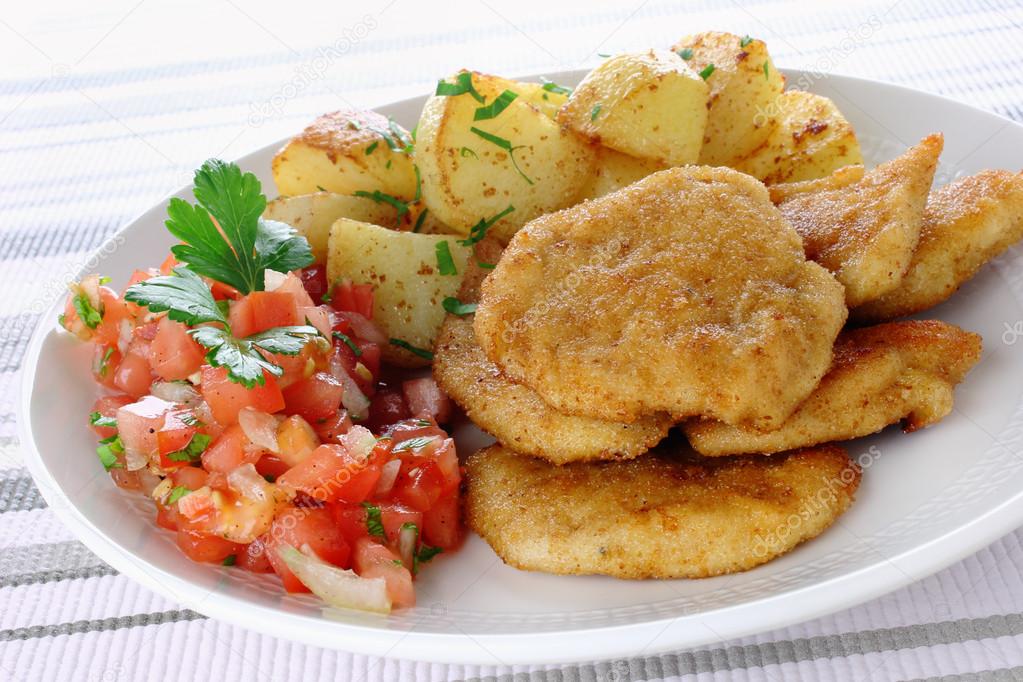 Pechuga de pollo empanada y frita, papas al horno y ensalada de tomate 2023