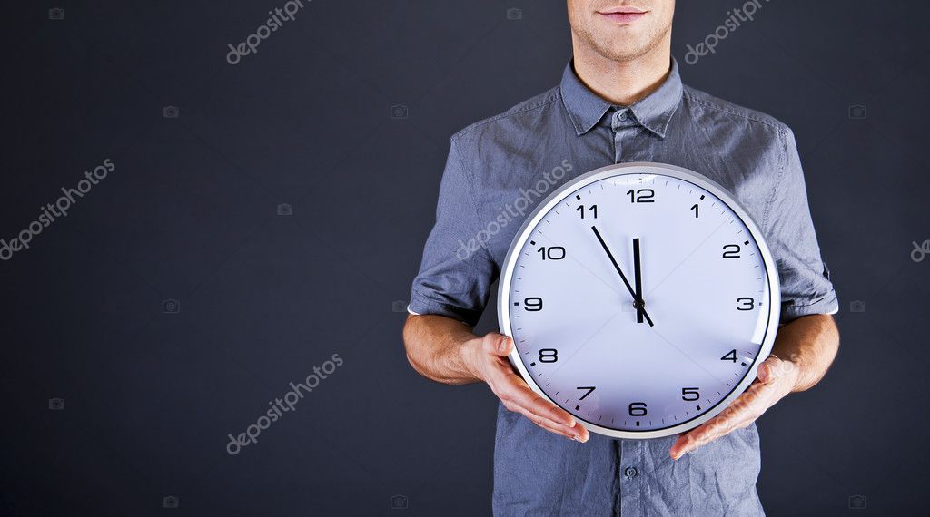Man holding wall clock over dark background Stock Photo by ©wisiel 24472431