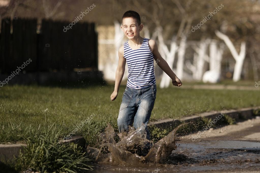 Little boy jumping in puddle Stock Photo by ©ababaka 42849261