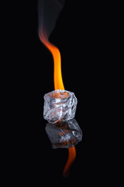Ice cube with flame on shiny black surface - Stock Image - Everypixel