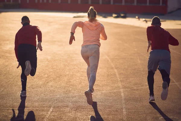 group of three caucasian, two men and one woman, racing at the athlete ...