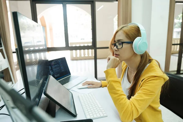 Young woman programmer sitting at table in front of laptop, sleepy ...