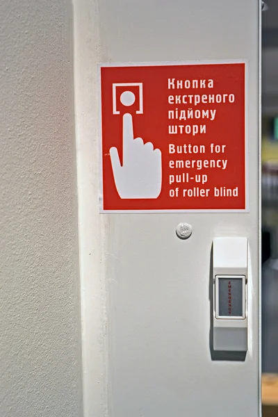 Red button for emergency roller pull-up on the wall, security details ...