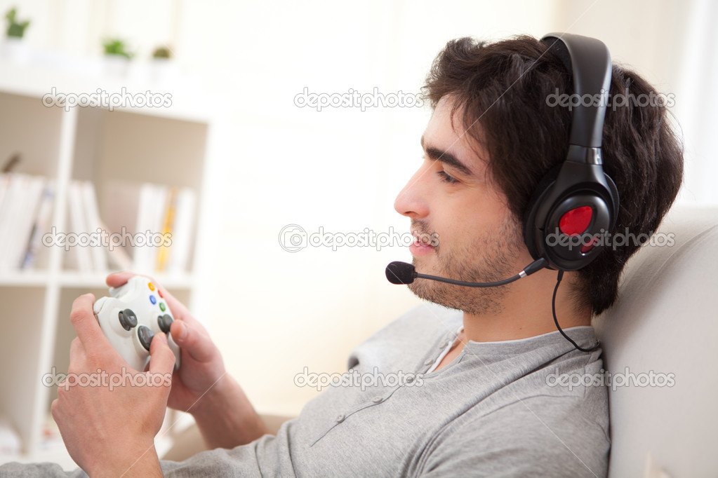 Young attractive man playing video games online in a sofa — Stock Photo ...