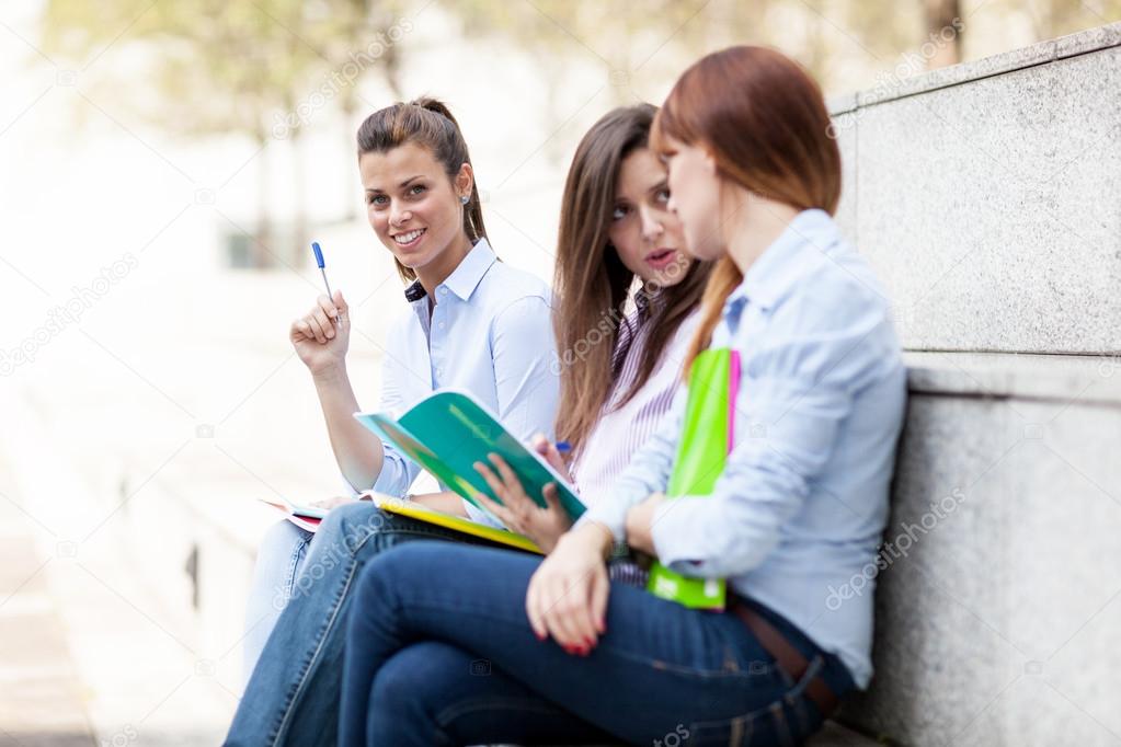 Three female students sitting on a bench with notebooks — Stock Photo ...