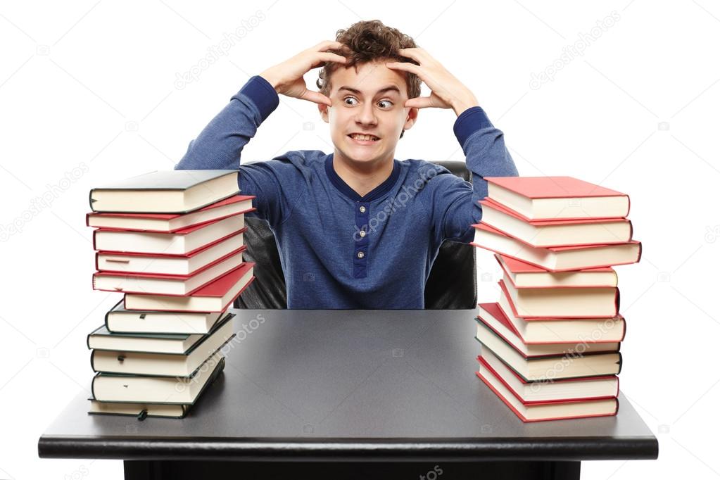 Angry stressed student sitting at his desk with hands on the head ... Angry stressed student sitting at his desk with hands on the head ...