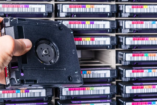hand of a technician holding data storage magnetic tape in front of ...