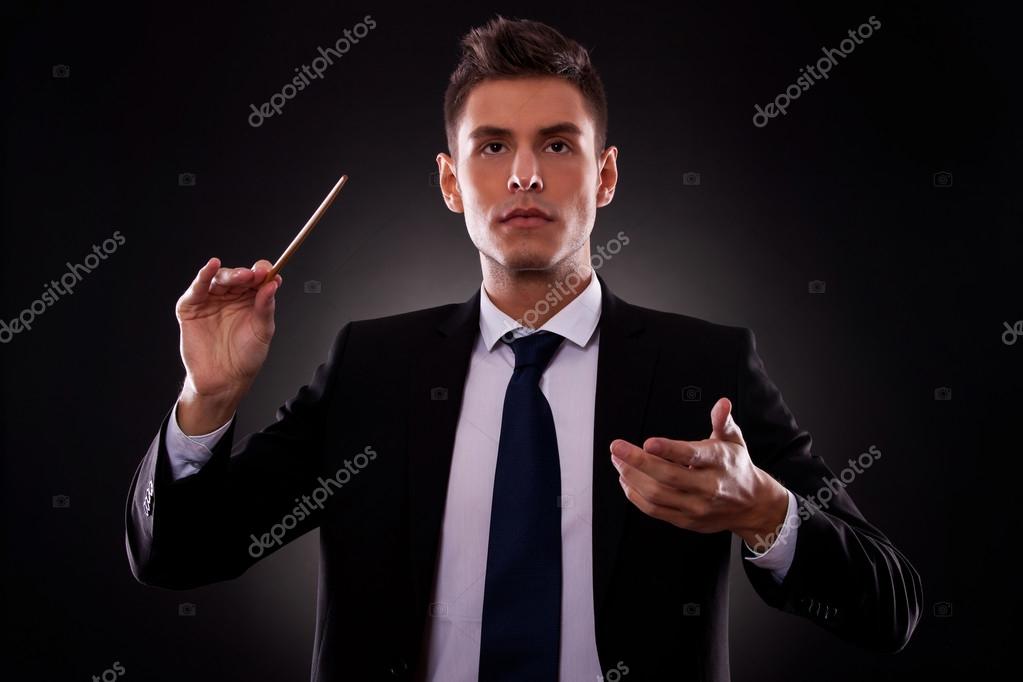Young businessman directing with a conductor's stick — Stock Photo ...