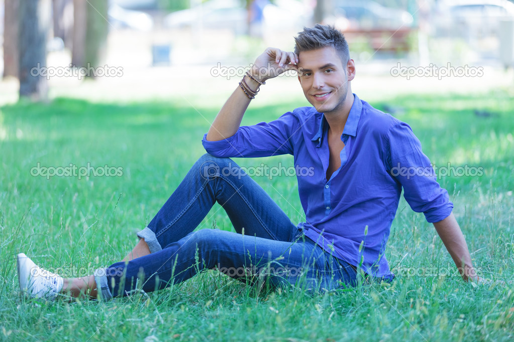 Seated man in grass smiles at you Stock Photo by ©feedough 22830364