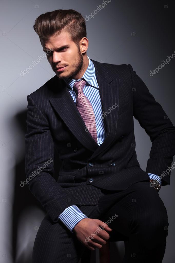 Angry young business man in classic suit and tie sitting — Stock Photo ...