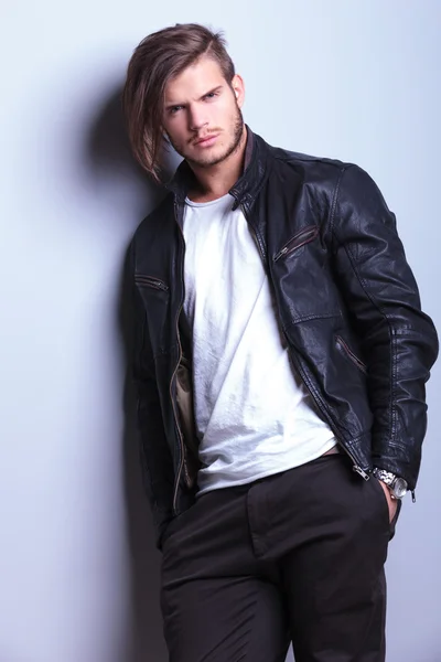 Serious man in leather jacket standing against gray wall Stock Photo by ...