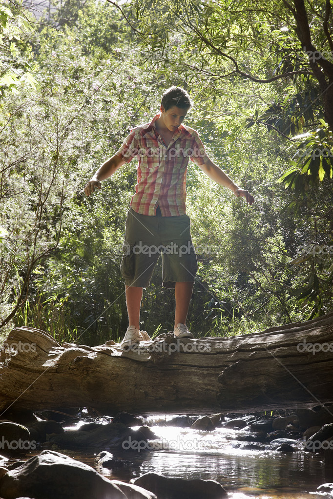 Young Man Walking On Log Over Stream Stock Photo by ©londondeposit 21786793