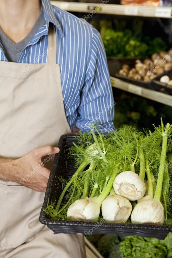 Sección media del hombre sosteniendo cesta de cebolla verde en el ...