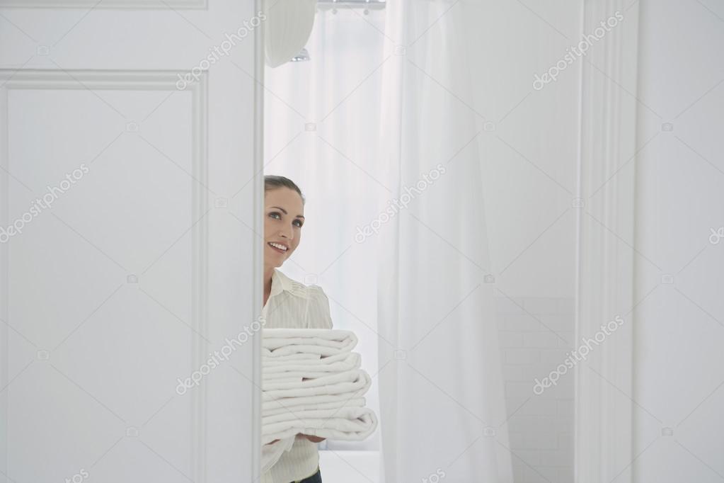 Woman carrying folded linen in home Stock Photo by ©londondeposit 33834521