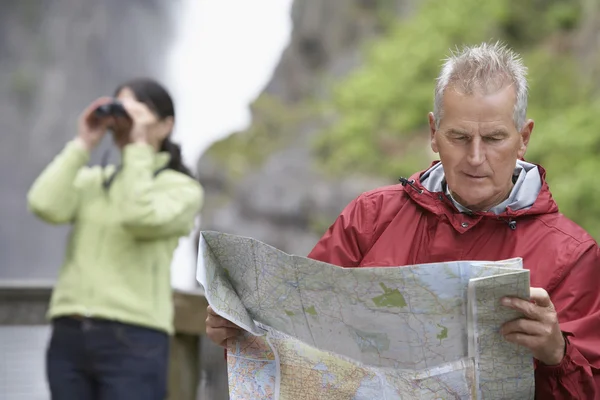 Man reading map, woman looking through binoculars - Stock Image ...