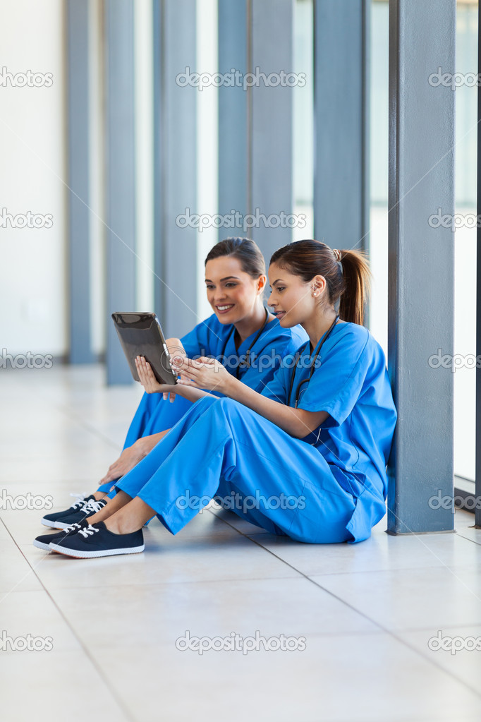 Female nurses using tablet computer during break Stock Photo by ...