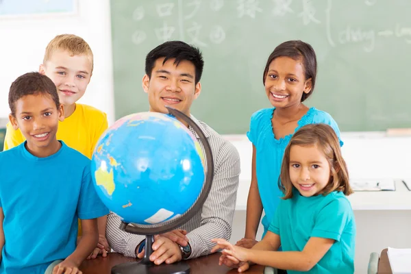 Primary school geography teacher and students with a globe - Stock ...