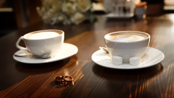 Two cups of coffee on the table, with wedding rings. - Stock Image ...
