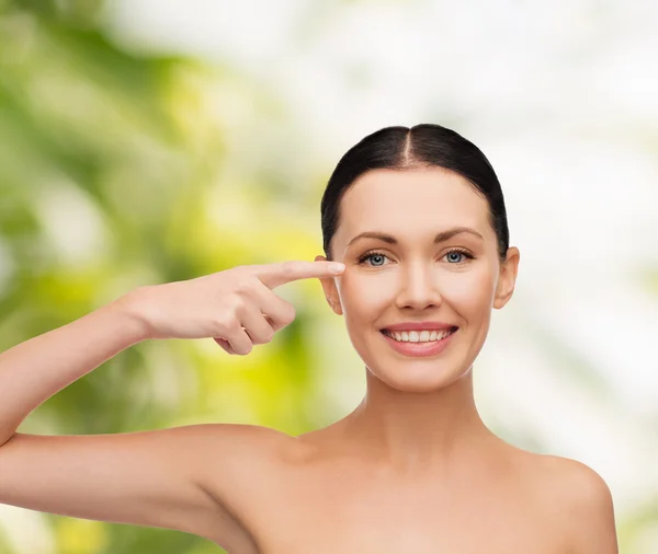 Young calm woman pointing to her eye - Stock Image - Everypixel