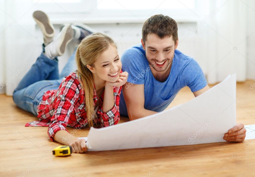 Smiling couple looking at blueprint at home — Stock Photo © Syda ...