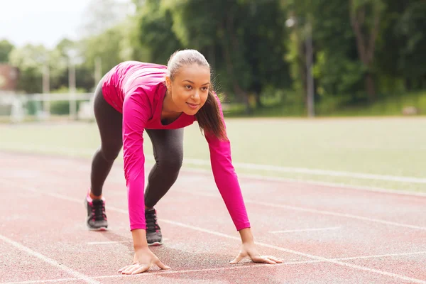 smiling young woman running on track outdoors - Stock Image - Everypixel