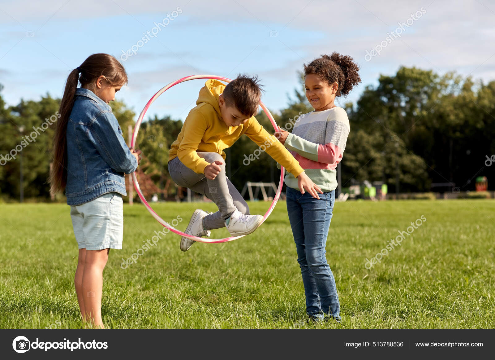 Happy children jumping through hula hoop at park Stock Photo by ©Syda ...