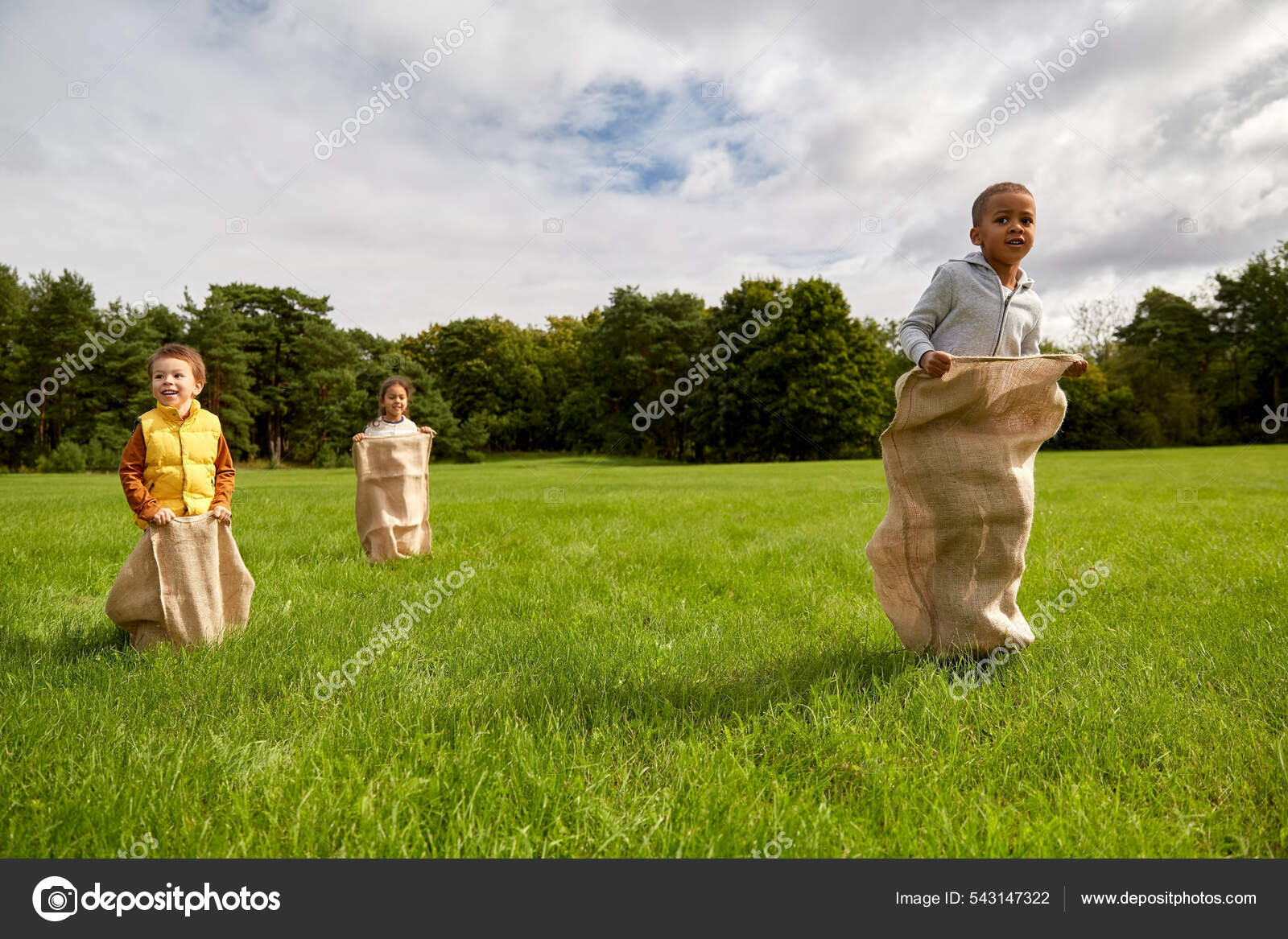 Happy children playing bag jumping game at park Stock Photo by ©Syda ...