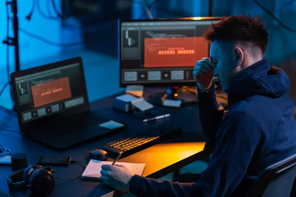 cybercrime, hacking and technology concept - male hacker in dark room ...