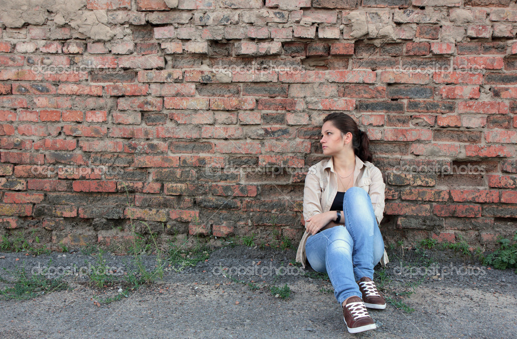 Sad Girl Sitting Against Wall