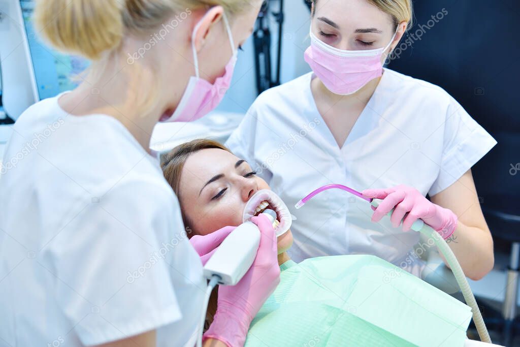 Mujer dentista y asistente escaneando los dientes del paciente con ...